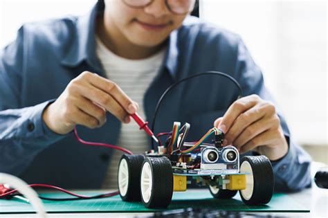 집에서 로봇 팔과 로봇 자동차 숙제 프로젝트를 하는 아시아 십대 학생들이 회로와 코딩을 조립합니다 로봇 공학 및 Stem 교육