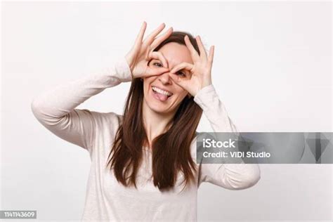 눈 가까이 손을 잡고 빛 옷에 재미 젊은 여자 안경 또는 쌍안경 흰색 배경에 고립 된 표시를 모방 사람들은 진심으로 감정 라이프 스타일 개념입니다 복사 공간을 모의 합니다