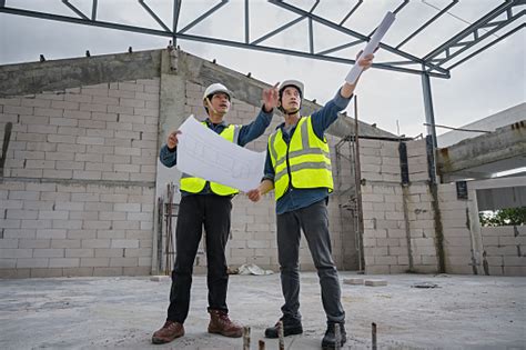 토목 엔지니어는 청사진에 대해 건설 현장의 구조를 검사하고 건물 검사관은 토목 엔지니어와 함께 건물 구조를 검사합니다 토목 엔지니어 홀드 청사진 검사 건물 20 24세에