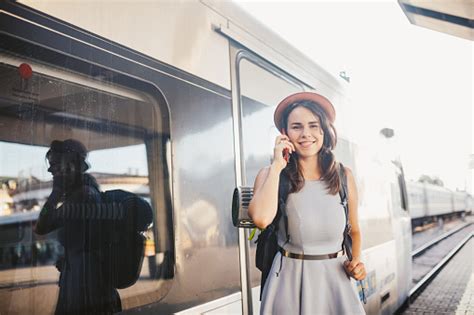 테마 교통 및 여행 Toothy 미소 서 세로 젊은 백인 여자 배낭 기술을 사용 하 여 역 기차 배경 기차 드레스와 모자 여름에 전화 손을 스마트 가격에 대한 스톡 사진 및