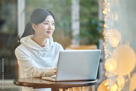 아시아 한국의 카페 테이블에 앉아서 노트북을 바라보며 강의를 듣거나 숙제 또는 일을 하는 젊은 여자 대학생 모델 Photos Adobe Stock