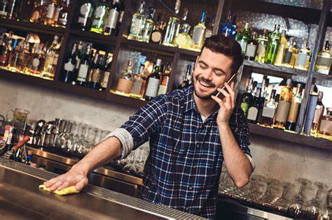 젊은 바텐더 서 에 바 카운터 이야기 에 스마트 폰 청소 테이블 즐거운 바에 대한 스톡 사진 및 기타 이미지 바 밤 하루 시간대 청소하기 Istock