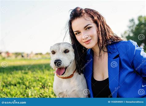 Linda Jovem Sentada Na Grama Abraçando Seu Cachorro No Parque Imagem De