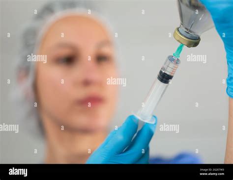 Young Female Health Worker Fills A Syringe With Saline For Injection In