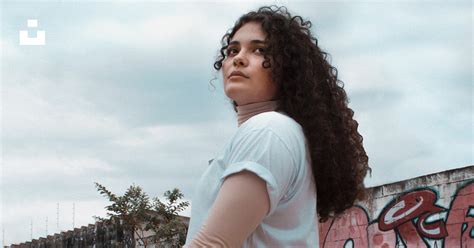 흰 티셔츠와 회색 바지를 입은 여자가 갈색 나무 좌석에 앉아 있다 사진 Unsplash의 무료 브라질 이미지