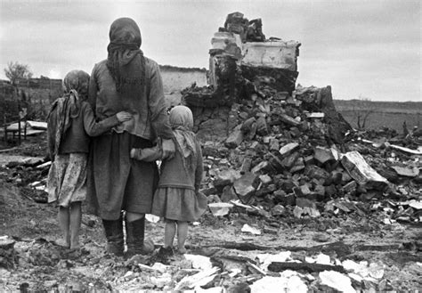 Женщина с двумя девочками смотрит на руины родного дома — военное фото