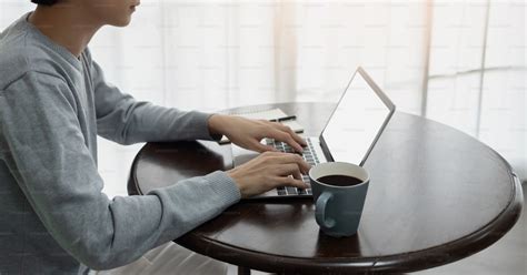 스웨터를 입은 아시아 청년은 집에서 직장에 있는 둥근 나무 책상에서 노트북 컴퓨터를 사용하고 있다 타이핑 구직 무선 기술과의 연결 사진 Unsplash의 인터넷 이미지