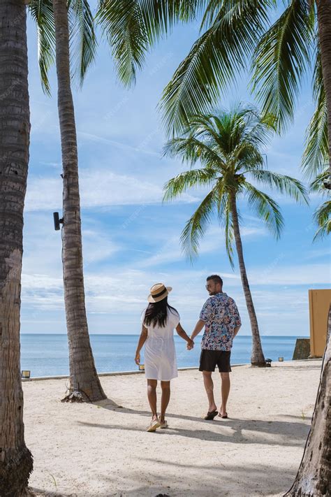 Premium Photo Men And Women Walking On A Tropical Beach With Palm