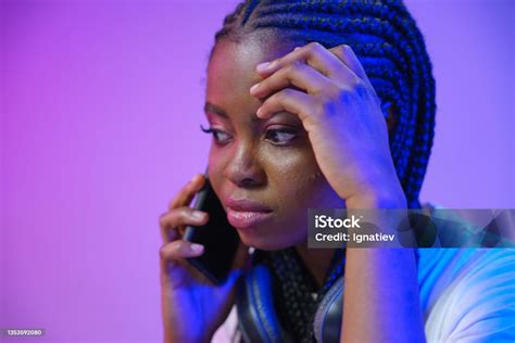 보라색 배경이있는 녹음 스튜디오에서 휴대 전화로 그녀의 목에 헤드셋을 가진 화가 젊은 아프리카 여성 우리는 클로즈업에서 그녀를