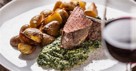 레드 와인은 구운 감자 시금치 딥 신선한 샐러드를 곁들인 붉은 고기 수비드 스테이크에 전형적인 비키어로 나무 책상 위의 백자