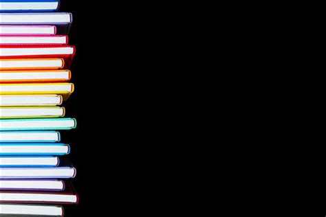 کتاب‌هایی با جلد کتاب‌های رنگارنگ روی هم چیده شده‌اند جدا شده روی پس‌زمینه سیاه الگوی آموزشی یا