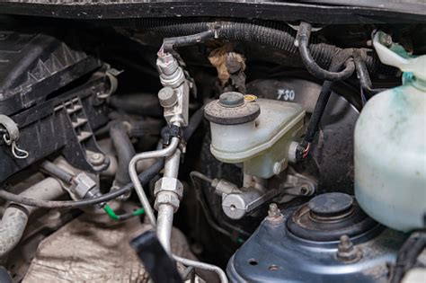 차량의 수리 및 유지 보수를 위해 작업장에서 차량의 엔진 실에 레벨 센서와 전선 전기가 있는 오일로 얼룩진 브레이크 유체 탱크 자동차 서비스 산업 브레이크에 대한 스톡 사진