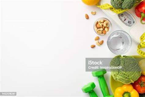 슬리밍 개념 물 야채 양배추 토마토 고추 아몬드 캐슈 너트 비늘과 아령의 줄자 유리 카피 스페이스가 있는 격리된 흰색 배경에 있는 상위 뷰 사진 다이어트에 대한 스톡 사진