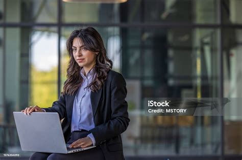 진지한 비즈니스 우먼은 열심히 일하고 노트북에서 비즈니스 문제를 해결한다 그녀는 현대 사무실 센터 근처의 야외에 앉아 있습니다 건물 외관에 대한 스톡 사진 및 기타 이미지