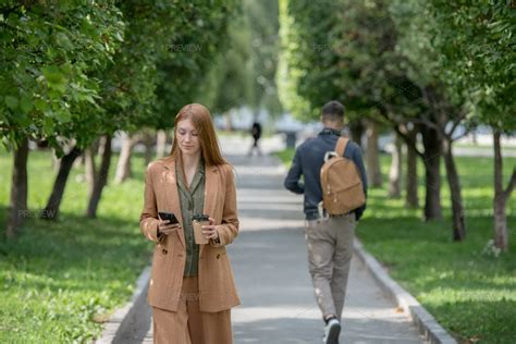 Businesswoman Scrolling On Her Smartphone While Moving Along The Park