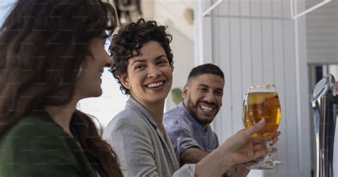 한 무리의 친구들이 어울리고 옥상의 바에서 맥주와 함께 건배를 하고 있습니다 사진 Unsplash의 공생 이미지