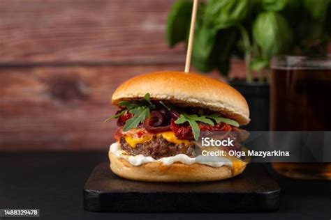 쇠고기 치즈 튀긴 베이컨 야채 햇볕에 말린 토마토 캐러멜 양파 마요네즈 로켓 샐러드 얇게 썬 롤빵으로 만든 홈메이드 버거 또는