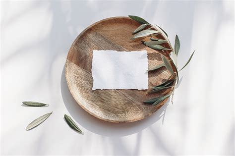 여름 웨딩 문구 모형 장면 빈 명함 햇빛에 초대 나무 접시 올리브 가지와 잎이 있는 트레이가 햇볕에 들어있습니다 흰색 테이블