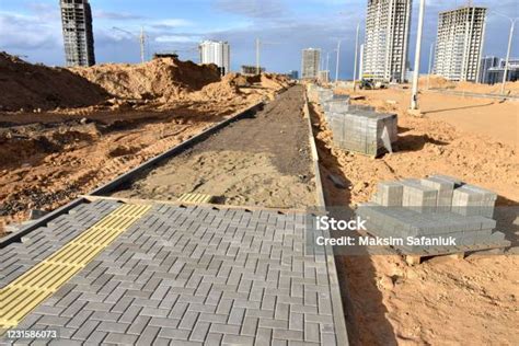 건설 현장에서 포장 슬래브를 누워 마을 보행자 구역에 포장 벽돌을 설치하는 과정 콘크리트 블록을 설치하기 위해 모래를 규준 도로 공사용 포장 개조 공사 개선에 대한 스톡