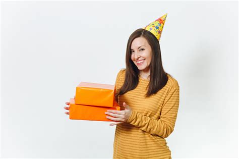 아름 다운 백인 재미 젊은 행복 한 여자 노란색 옷을 입고 생일 파티 모자 현재와 함께 주황색 선물 상자를 들고 축 하 하 고 광고에 대 한 격리 하는 흰색 바탕에 휴가