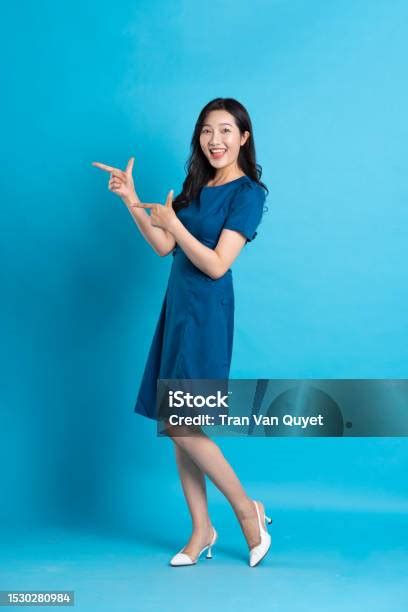 파란 드레스를 입은 아름다운 여인의 초상화 파란 배경에 고립 가리키기에 대한 스톡 사진 및 기타 이미지 가리키기 서 있기 여성 Istock