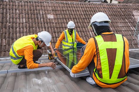집 지붕에 태양전지를 설치하는 서비스 엔지니어 야외에서 태양 전지판 시스템에 대해 작업하는 기술자 청정 및 재생 가능 에너지 개념 건축하기에 대한 스톡 사진 및 기타 이미지