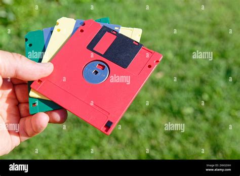 Vintage Colored Floppy Disks In A Hand On Green Grass Lawn Background