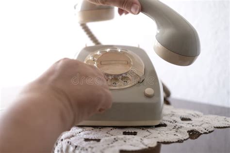 Mature Female Hand Removing Handset Rotating Dialer On Old White Rotary Telephone With Disc