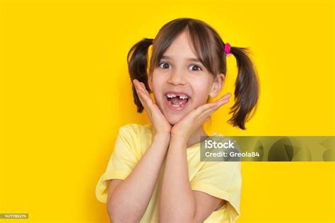 노란 위에 재미있게 놀고 있는 아기 이빨 미소를 가진 놀란 귀여운 소녀의 초상화 6 7 살에 대한 스톡 사진 및 기타 이미지 6 7 살 Edentulous T 셔츠