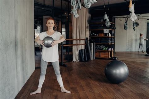 Premium Photo Serene Redhead Woman Holding A Medicine Ball In A