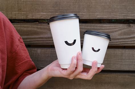 여성의 손에 커피와 흰색 종이 컵 도시에서 커피를 마실 시간입니다 커피갈기 순간을 즐기고 휴식을 취하십시오 일회용 종이 컵 클로즈업 맛있는 따뜻한 음료 텍스트 모형을 위한