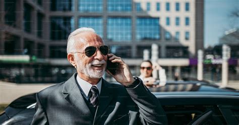 고급 자동차의 뒷좌석에 앉아있는 잘 생긴 고위 사업가 그는 차 문을 열고 나가거나 나간다 배경에 큰 버스가 부풀어 오른다 기업 비즈니스 개념의 교통 사진