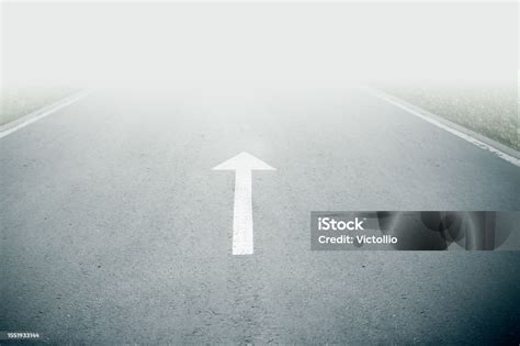 도로의 흰색 화살표 표지판이 안개에 들어갑니다 방향 표지판 앞으로 나아가는 개념 불분명하거나 부정적인 내일 개념 복사 공간이 비어 있습니다 0명에 대한 스톡 사진 및 기타