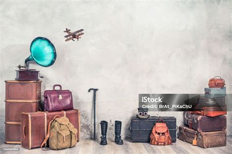 빈티지 클래식 골동품 가방 오래된 트렁크 수하물 배낭 가죽 부츠 실린더 모자 축음기 및 장난감 비행기 앞 콘크리트 벽 배경 여행