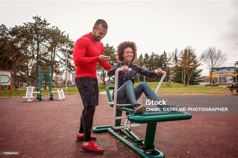 젊은 여자 선수는 그녀의 시간을 측정 하 고 격려 하는 피트 니스 코치와 함께 공원에서 조정 기계에로 잉 운동을 하 고 로잉 머신에 대한 스톡 사진 및 기타 이미지 Istock