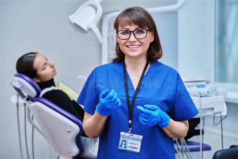 Portrait Of Female Dentist With Girl Patient Sitting In Dental Chair