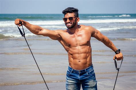 해변에서 행복한 젊은 아프리카 남자의 초상화 잘 생기고 자신감있는 남성적인 하드 피트니스 모델 남성 보디 빌더 식스 팩 완벽한 복근 어깨 팔뚝 삼두근 가슴을 가진 인도