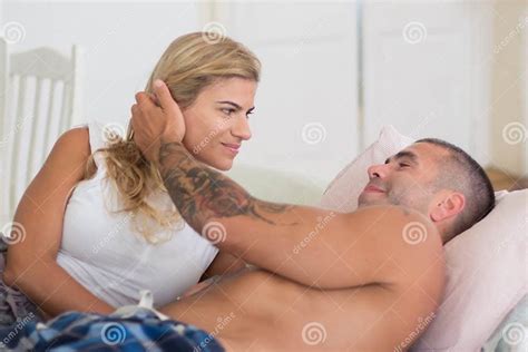 Man Stroking Wifes Hair While Lying In Bed In Morning Stock Image