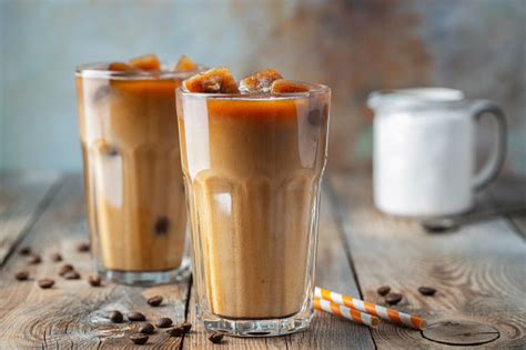 크림 위에 부 어 커피 얼음 조각 및 오래 된 소박한 나무 테이블에 콩 키 큰 유리에 커피를 얼음 블루 녹슨 배경 복사 공간에 튜브와 함께 추운 여름 음료 0명에 대한 스톡