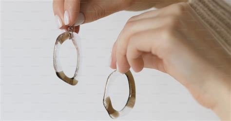 흰 벽을 배경으로 세련 된 현대 귀걸이를 들고있는 손 흰색 매니큐어를 가진 여성 손에 특이한 유행 융합 유리 귀걸이 현대적인 선물 사진 Unsplash의 귀고리 이미지