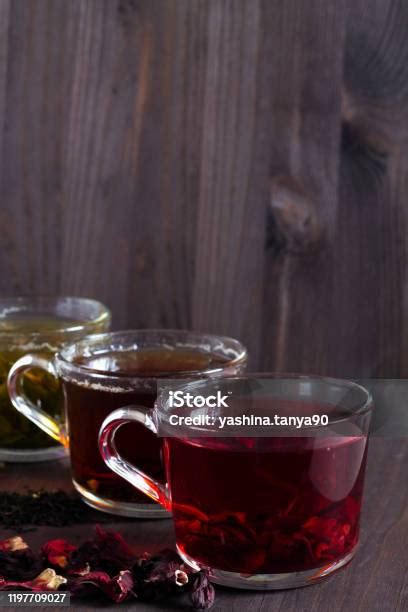레드 핫 히비스커스 차 건강한 라이프 스타일 뜨거운 음료 어두운 나무 배경에 마른 잎과 꽃이있는 검은 색 빨간색 및 녹차 3 잔 수직 방향 0명에 대한 스톡 사진 및 기타
