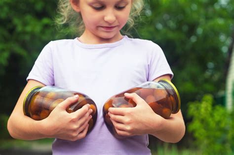 여자는 녹색 단풍의 배경에 수제 통조림 매화 콤포트와 두 항아리를 보유하고 8 9 살에 대한 스톡 사진 및 기타 이미지 8 9 살 건강한 식생활 계절 Istock