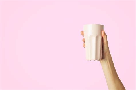 밝은 분홍색 배경에 뜨거운 커피 또는 차와 보라색 컵을 들고 여성의 손 따뜻한 커피 또는 차로 아침 식사 컨셉 겨울에 대한 스톡