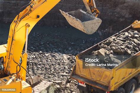 대형 노란색 굴 삭 기는 대형 주거 단지의 건설을 위한 기초 구 덩이를 파고 양동이는 땅을가 열 한다 대규모 기계를 구축 신축 공사의 초기 단계 0명에 대한 스톡 사진 및