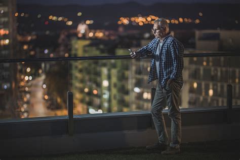 밤에 펜 트 하우스 테라스에서 휴대 전화를 사용 하 여 수석 남자의 전체 길이입니다 발코니에 대한 스톡 사진 및 기타 이미지 발코니 밤 하루 시간대 서 있기 Istock