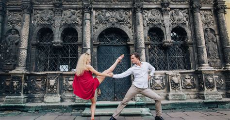 햇볕이 잘 드는 거리의 오래된 건물에서 포옹하고 춤을 추는 사랑에 빠진 아름다운 행복한 커플 세련된 힙스터 신랑과 빨간