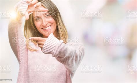 손으로 만드는 프레임 및 행복 한 얼굴로 손가락을 웃 고 고립 된 배경 위에 겨울 스웨터를 입고 젊은 아름 다운 여자 창의력과 사진 개념입니다 가을에 대한 스톡 사진 및