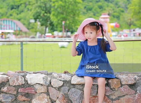 귀여운 아시아 소녀는 녹색 공원에 대 한 돌 벽에 밀 짚 모자를 착용 귀여운에 대한 스톡 사진 및 기타 이미지 귀여운 녹색 놀기 Istock