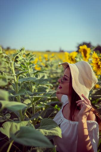 햇볕이 잘 드는 여름날 모자를 쓰고 해바라기 의 작물 밭에 서있는 흰색 드레스를 입은 젊은 여성의 초상화 감정에 대한 스톡 사진 및 기타 이미지 Istock