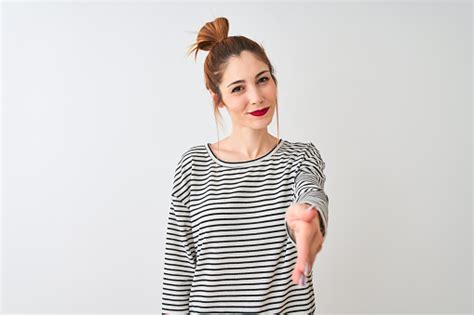 해군 줄무늬 티셔츠를 입은 빨간 머리 여성은 고립 된 흰색 배경 위에 서서 인사와 환영으로 악수를 제공합니다 성공적인 비즈니스 T 셔츠에 대한 스톡 사진 및 기타 이미지